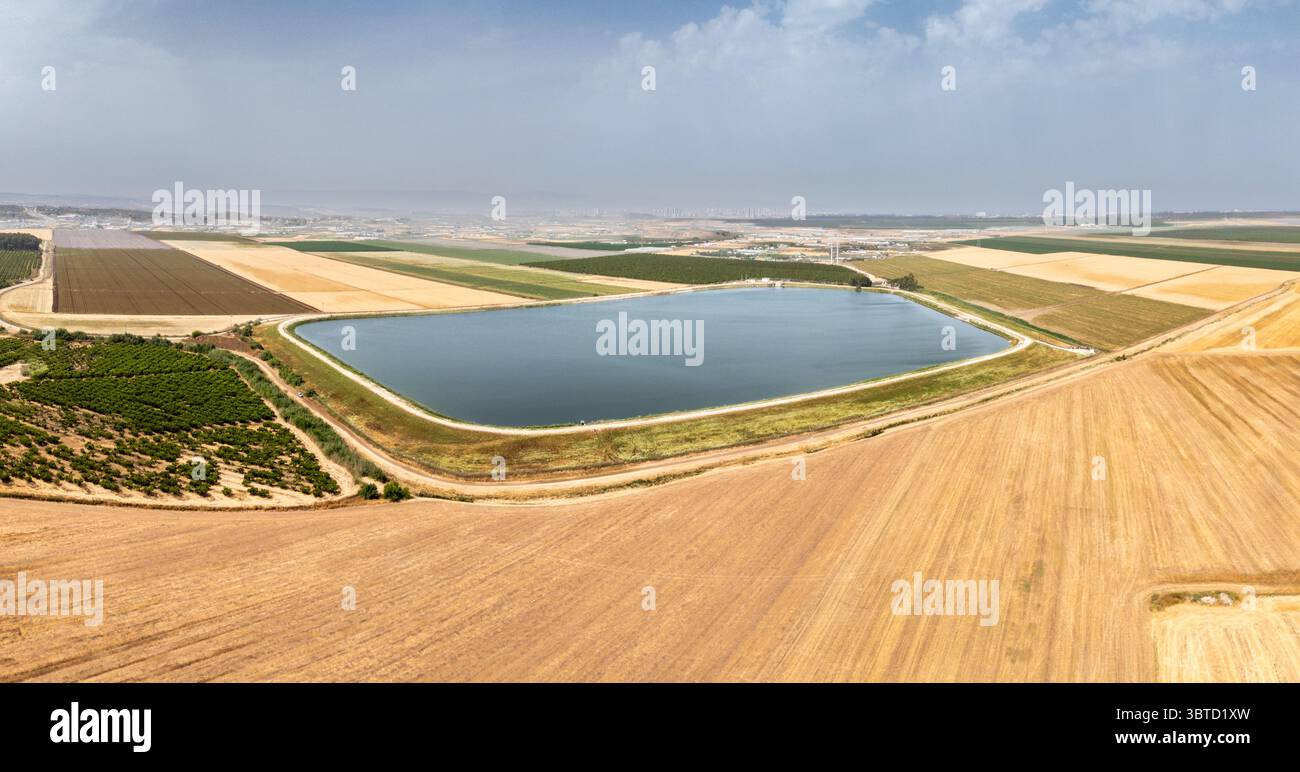 Aerial view of a serene reservoir reflecting the sky, surrounded by a ...