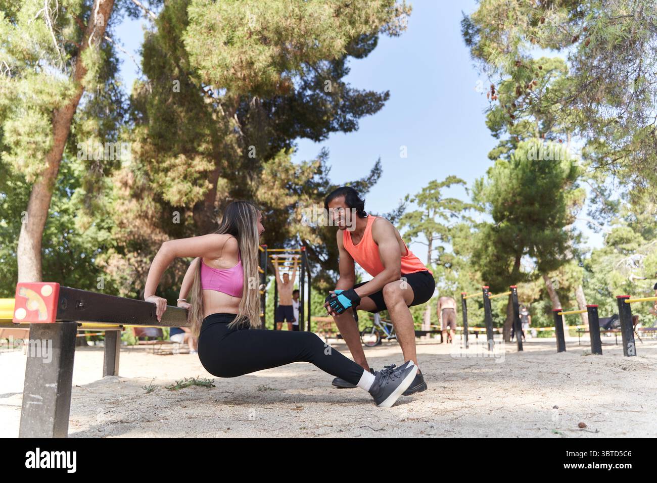 Personal trainer motivates a young woman performing dips in an outdoor ...