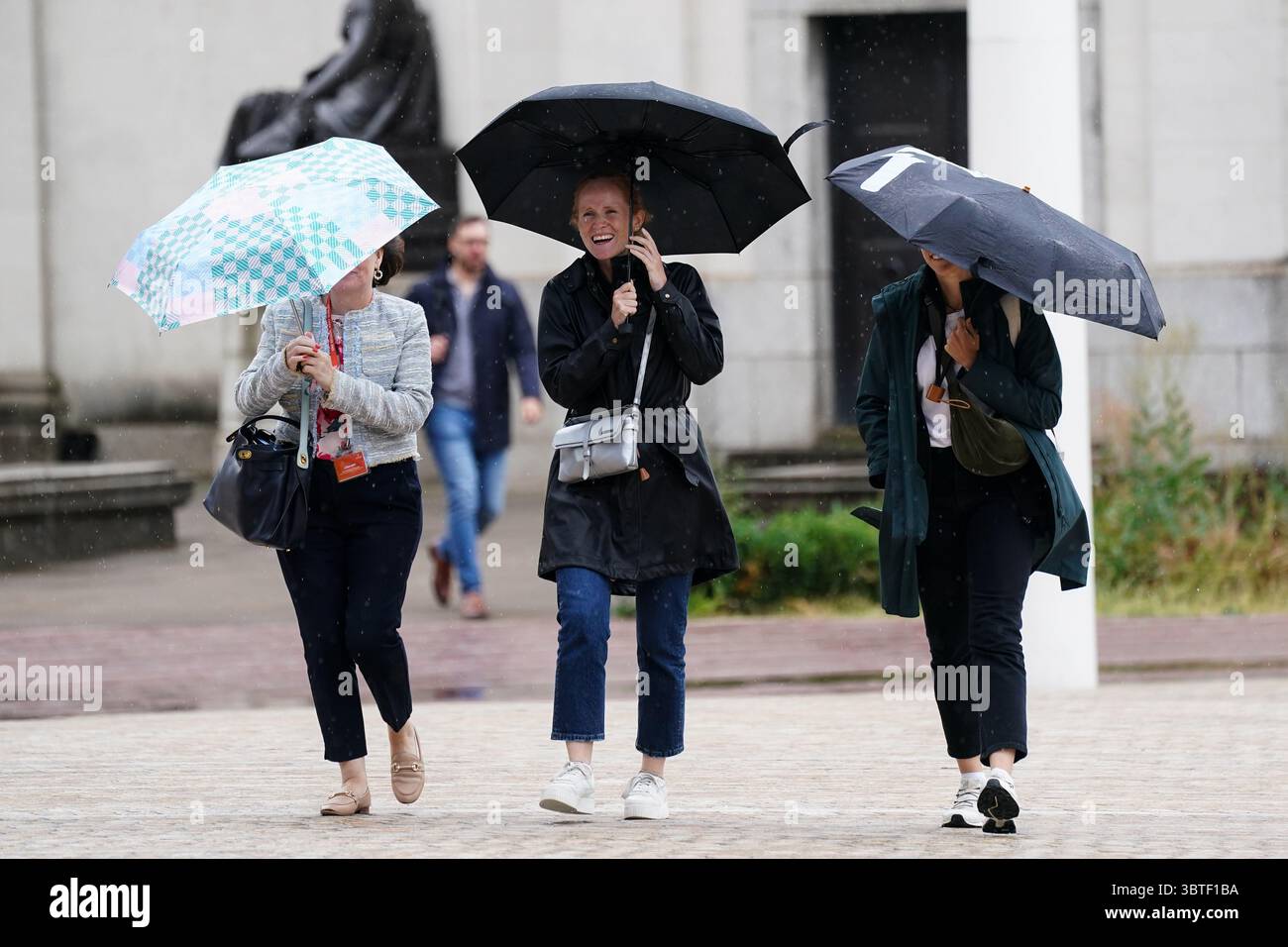 People use umbrellas as they walk by Centenary Square in Birmingham ...
