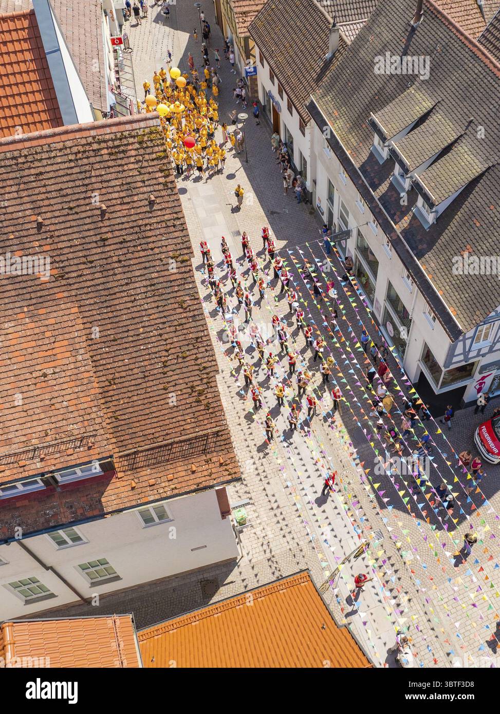 Aerial view of a colourful parade moving through the streets of a half ...
