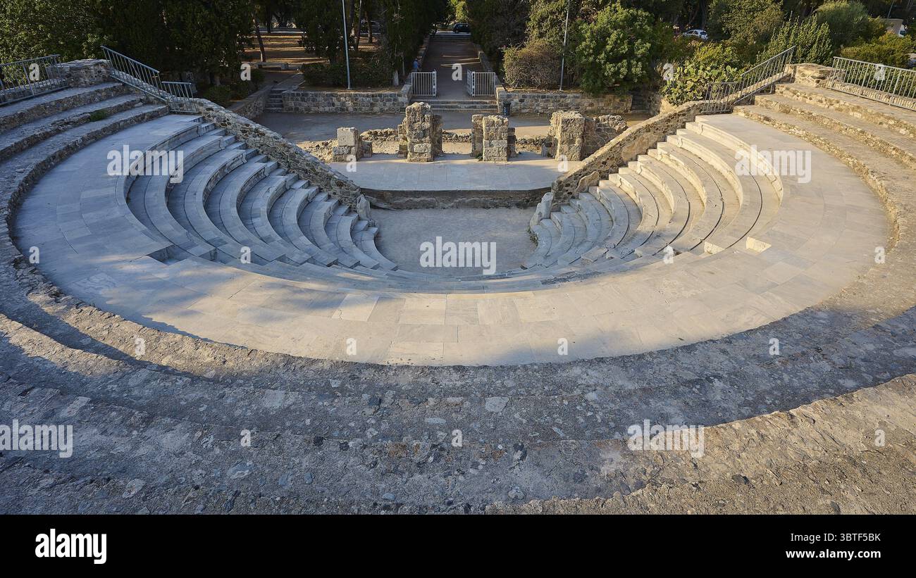 Round ancient theatre with ruined walls and stone steps surrounded by ...
