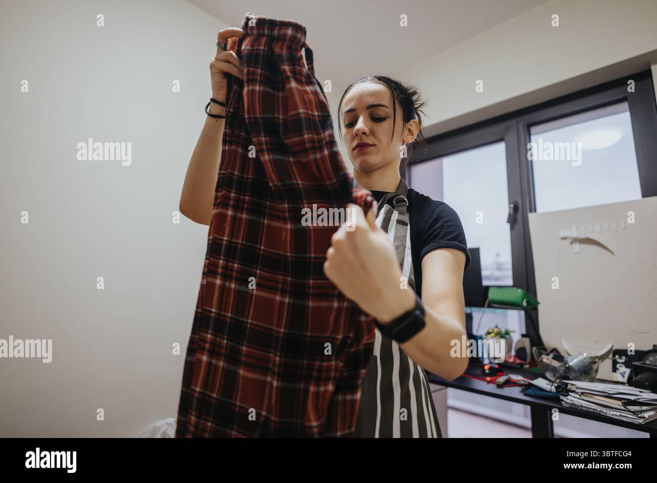 Young Woman Handling a Plaid Garment, Wearing an Apron in a Workshop ...