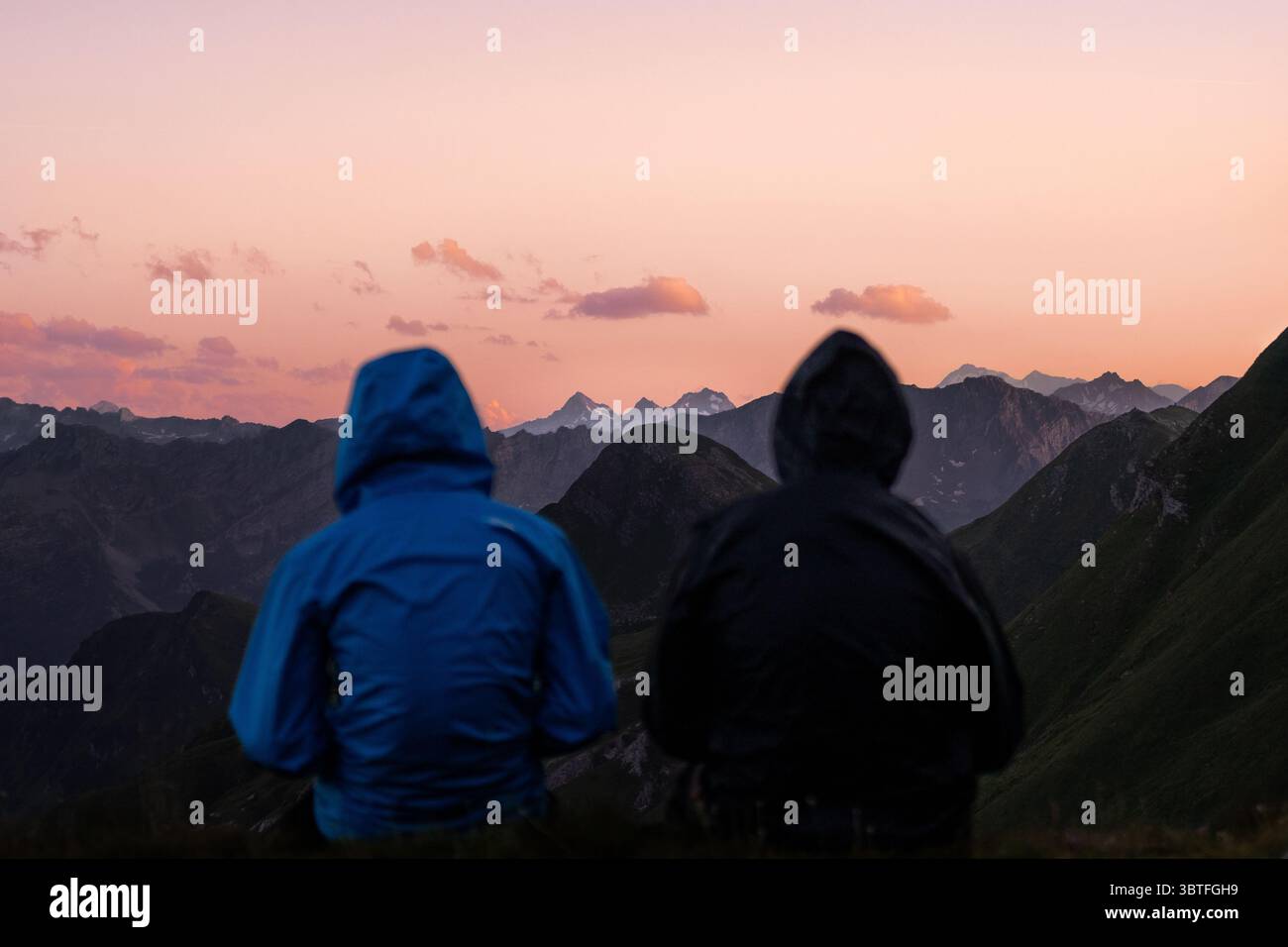 View of two figures silhouetted against a backdrop of purple-tinged sky ...