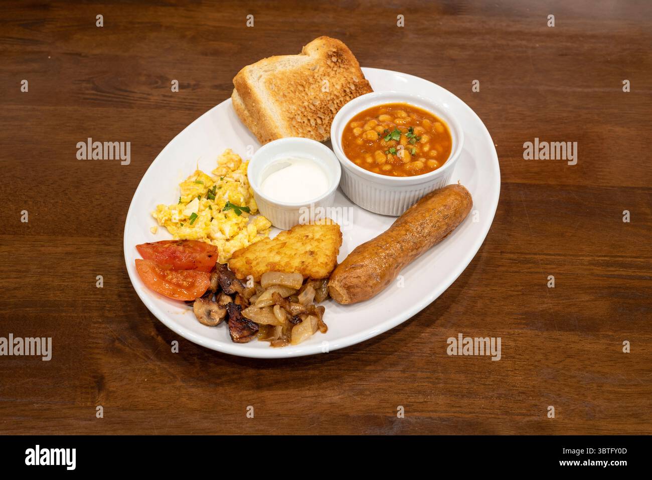 Traditional English breakfast with sausage, scrambled egg, baked beans ...