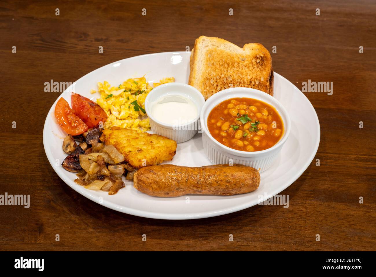 Traditional English breakfast with sausage, scrambled egg, baked beans ...