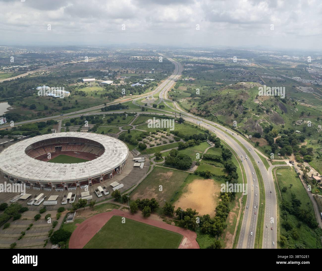 Aerial view of a large stadium nestled beside a sprawling highway ...
