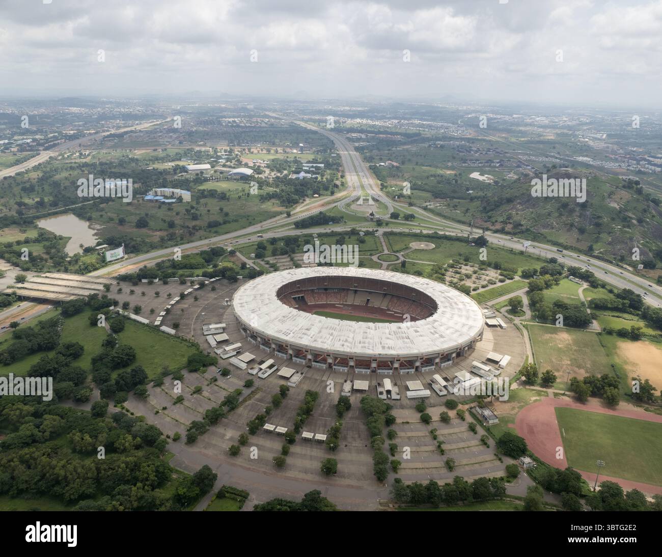 Aerial view of a stadium surrounded by green trees and roads stretching ...
