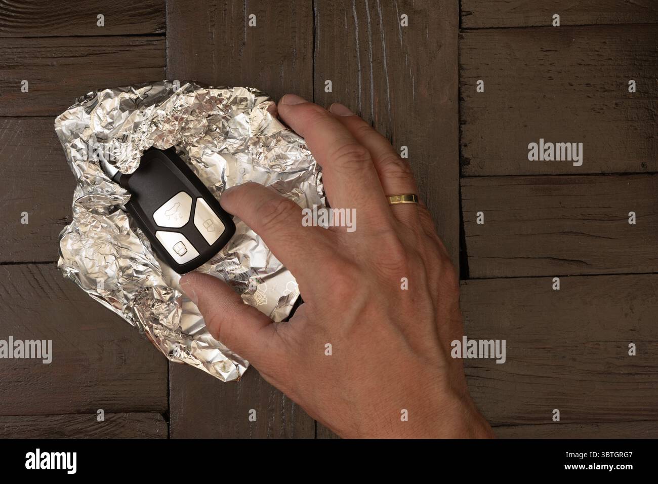 A man wraps his car keys in silver foil, trying to protect his car from ...