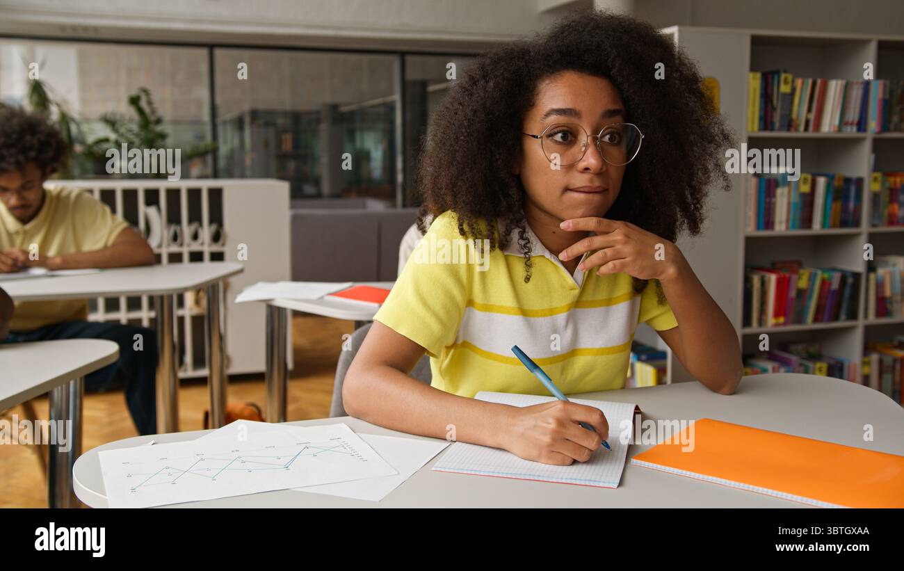 Concentrated African American woman girl female in classroom writing ...