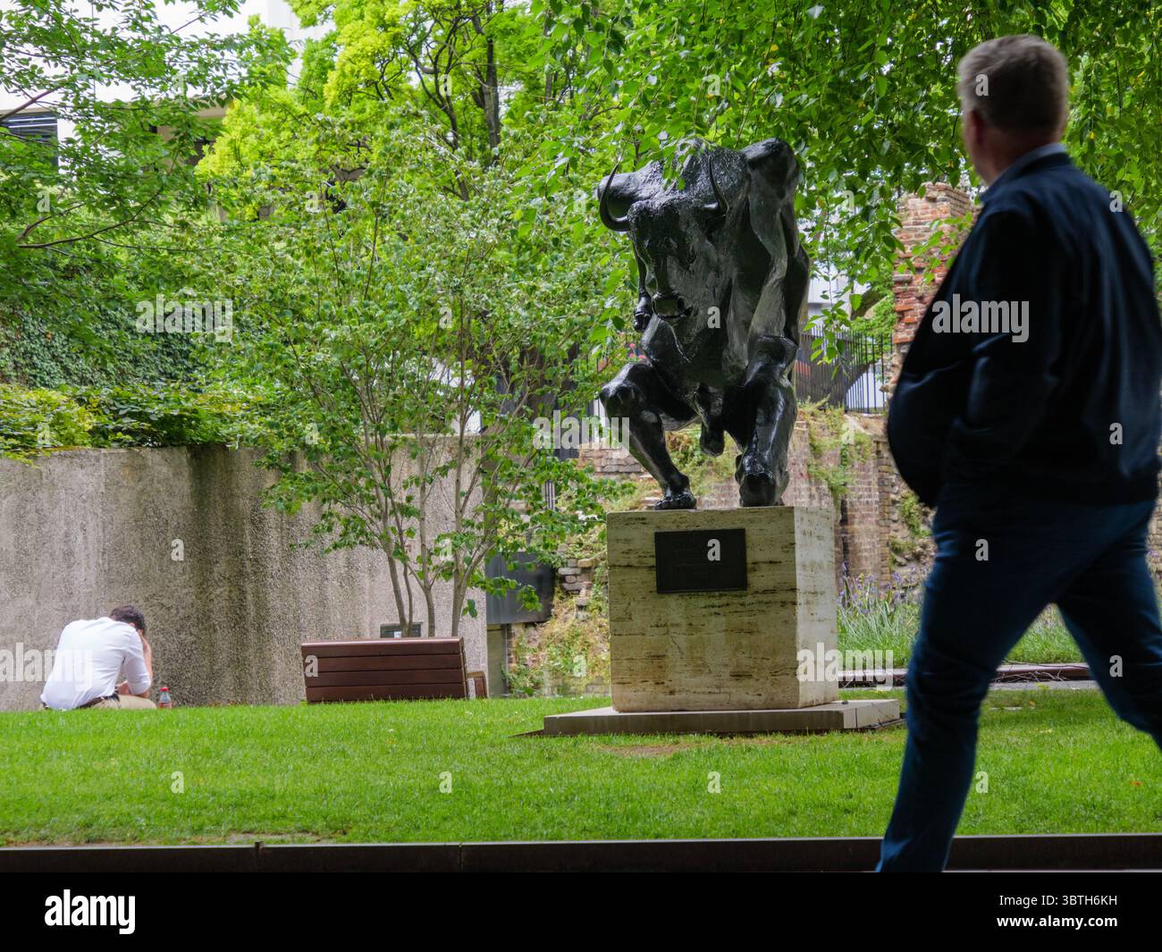 Pedestrians walk past the Minotaur statue in St Alphage Gardens, City ...