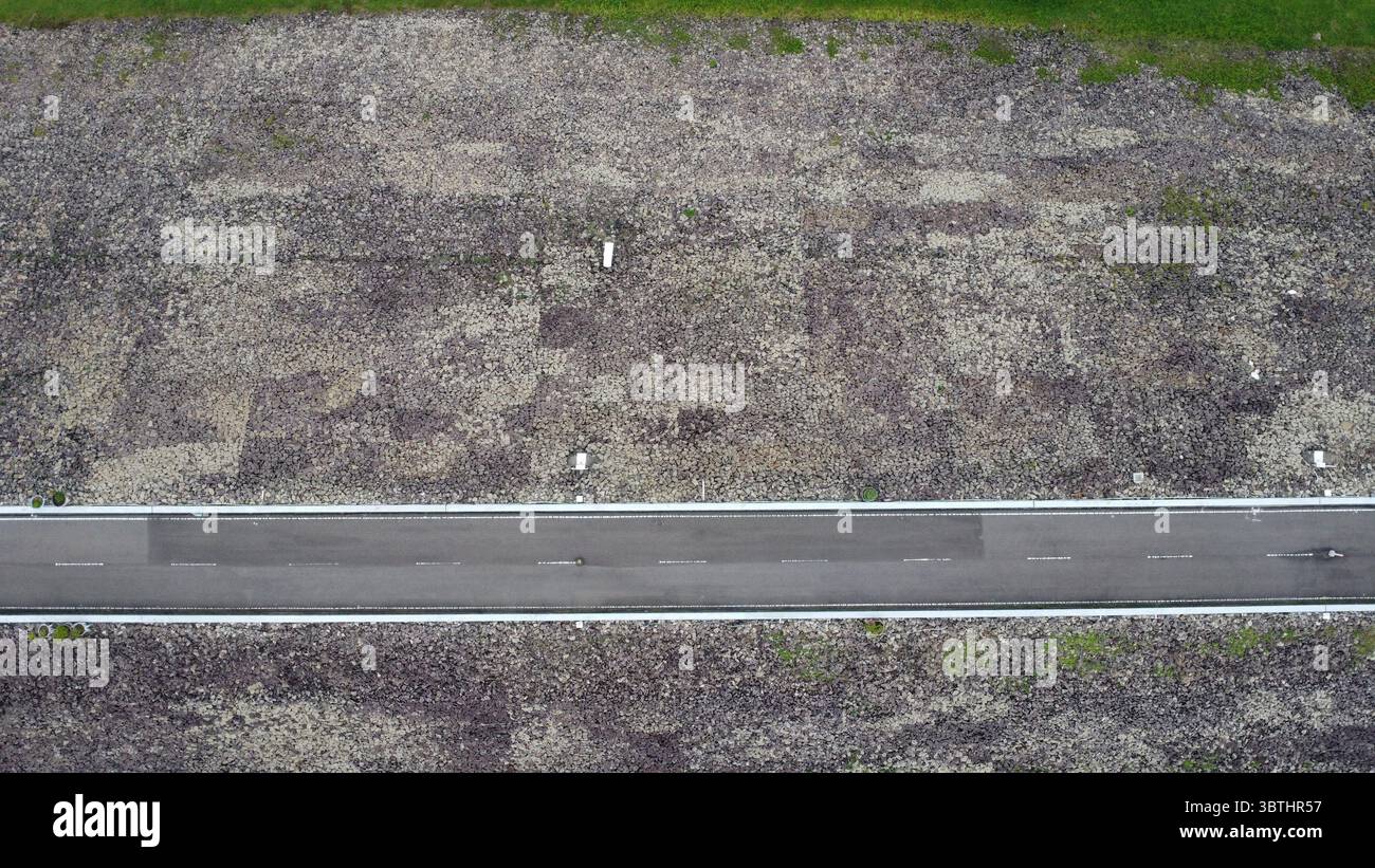 Aerial panorama showcases a straight road alongside a still water ...