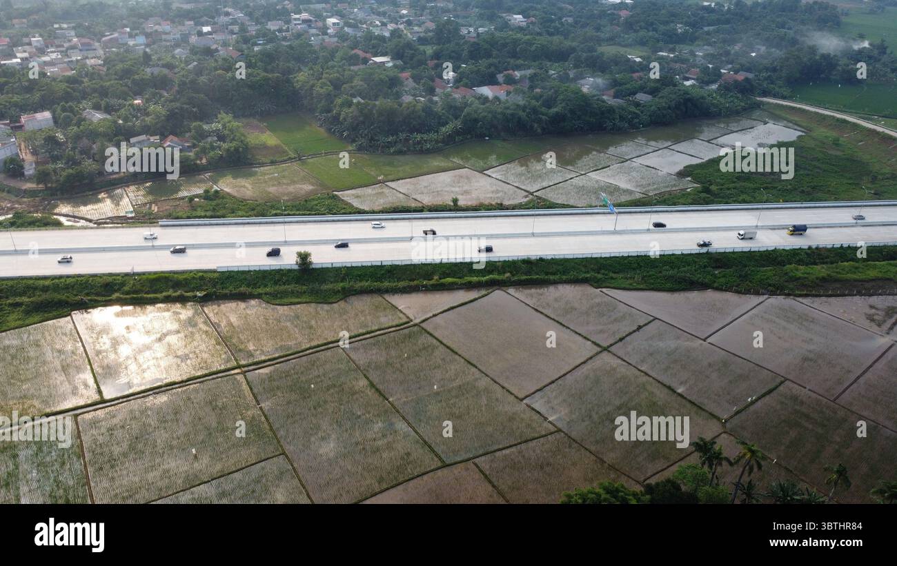 Elevated view showcases highway traffic amidst rice paddies, farmland ...
