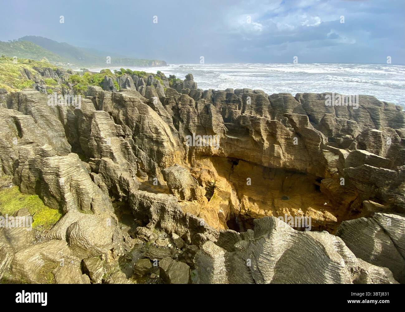 Powerful ocean spray erupts from a blowhole among layered limestone ...