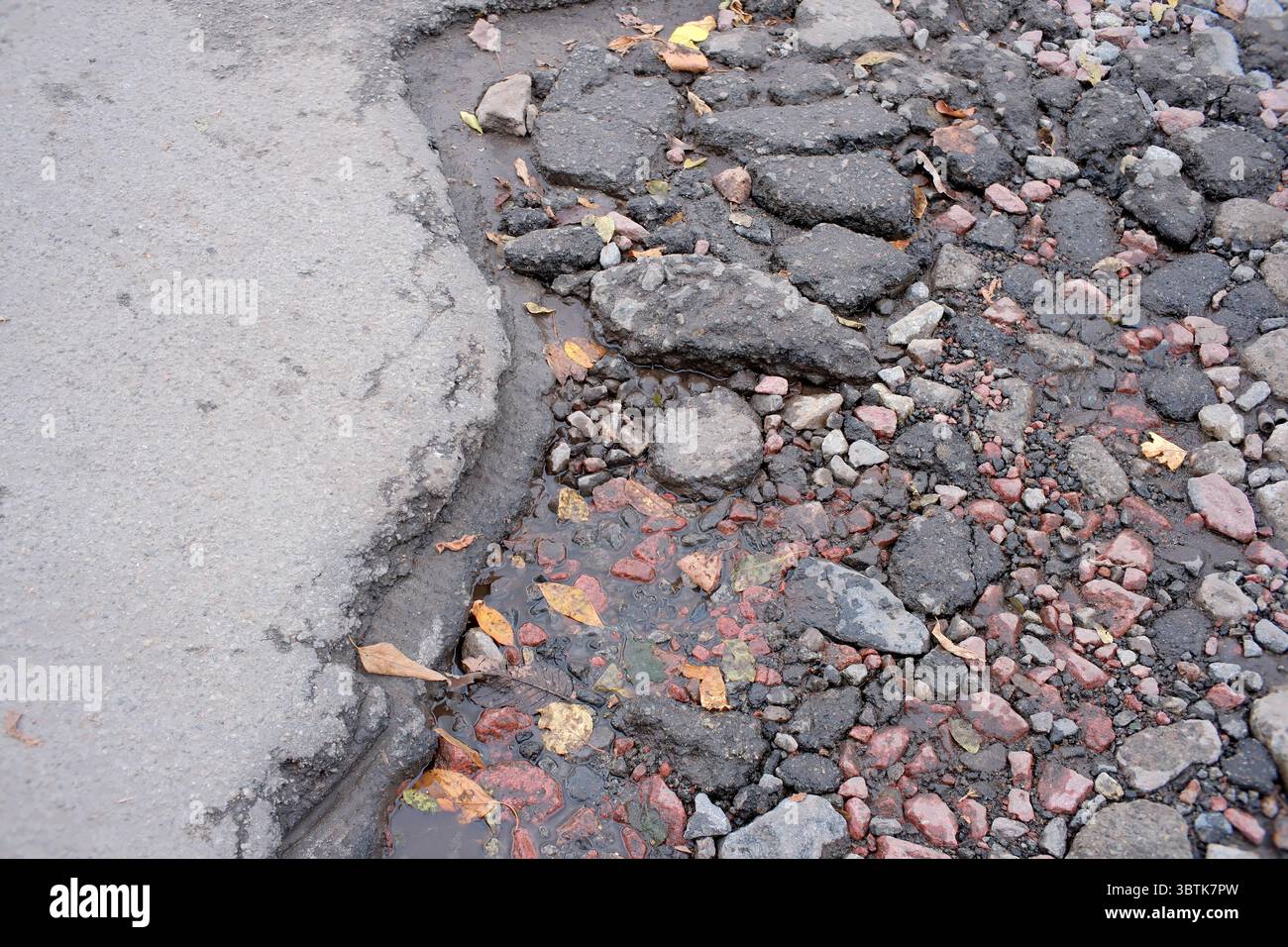 Damaged asphalt road surface on an autumn rainy day close-up, road ...