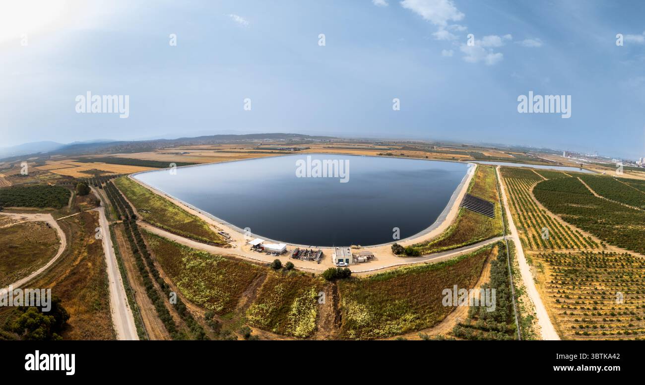 Aerial view of a reservoir reflecting the sky's soft hues amidst fields ...