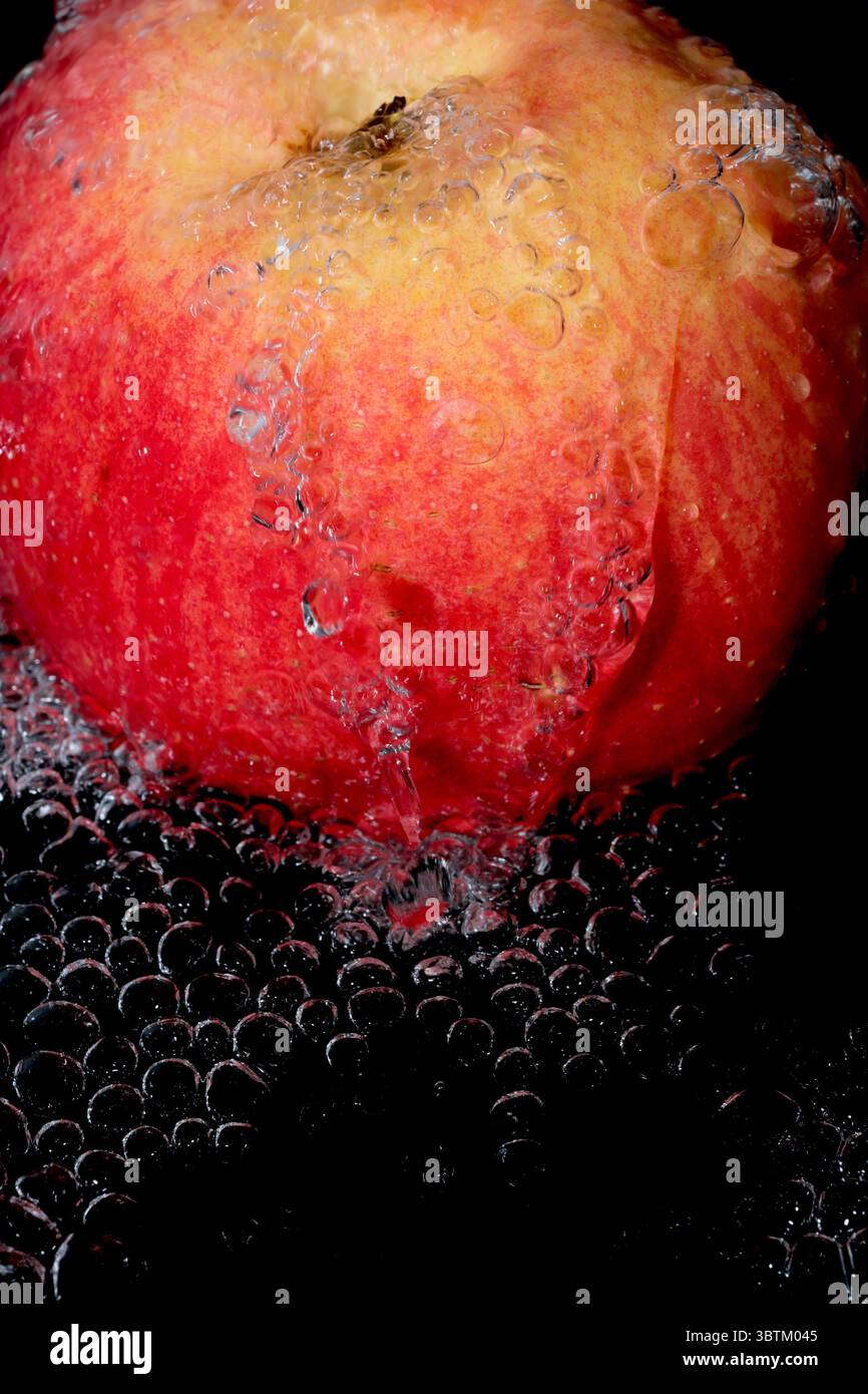 Red ripe sweet apple under a stream of clean tap water with the ...