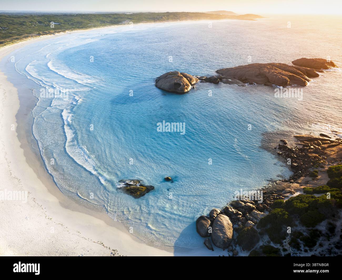 Aerial view of silky turquoise waters embrace rugged rocks and pristine ...