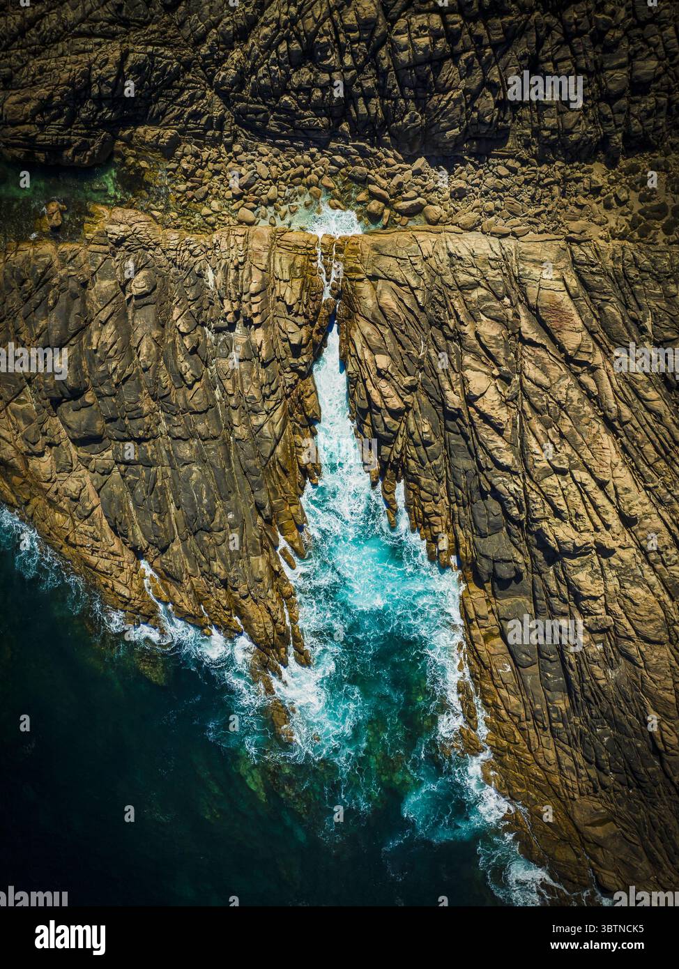Aerial view of rugged cliffs embrace the turquoise sea, where crashing ...