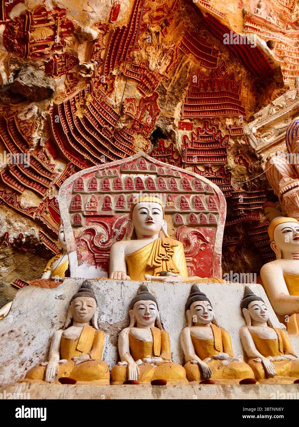 Buddha statues and intricate carvings inside Kawgon Cave, Hpa-An, Myanmar, creating a serene and ...