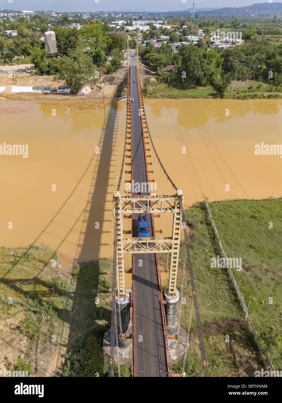 Aerial view of a long suspension bridge stretching across the muddy ...