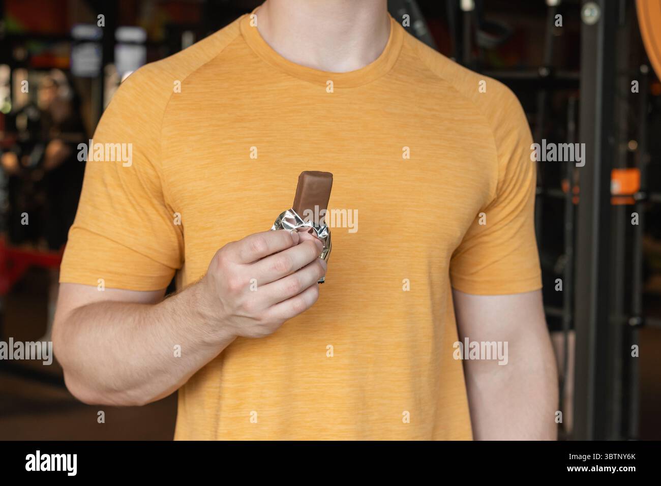 Bodybuilder or young man eating energy bar. Muscular athlete snacks ...