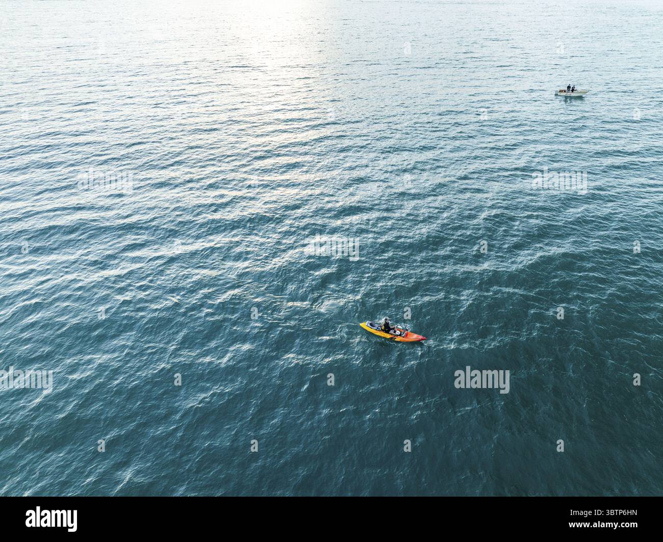 Aerial view of kayaks cutting through the glimmering, sun-kissed waters ...
