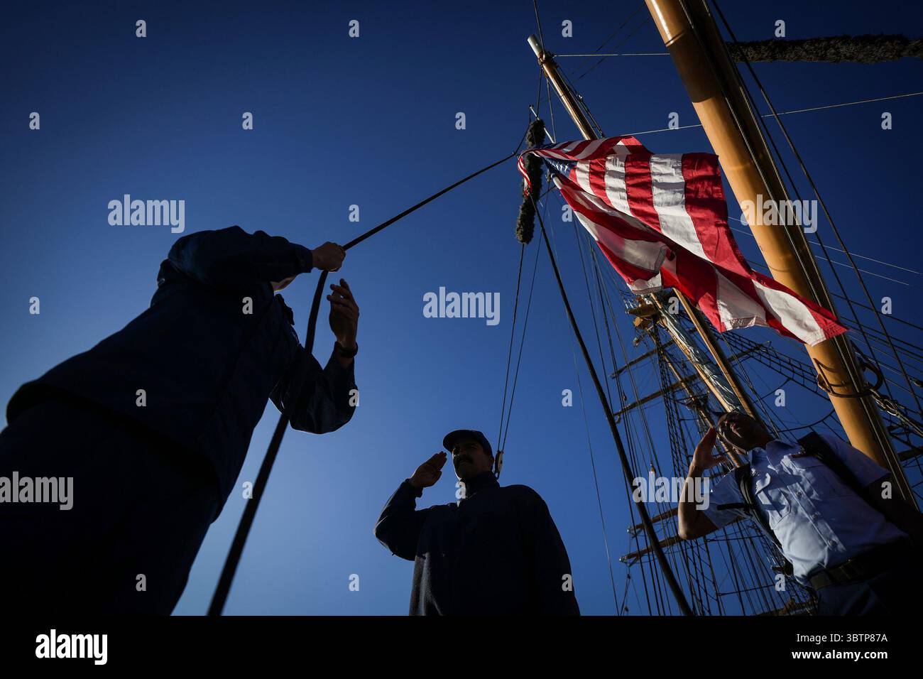 Members of the U.S. Coast Guard salute as the U.S. flag is raised on ...