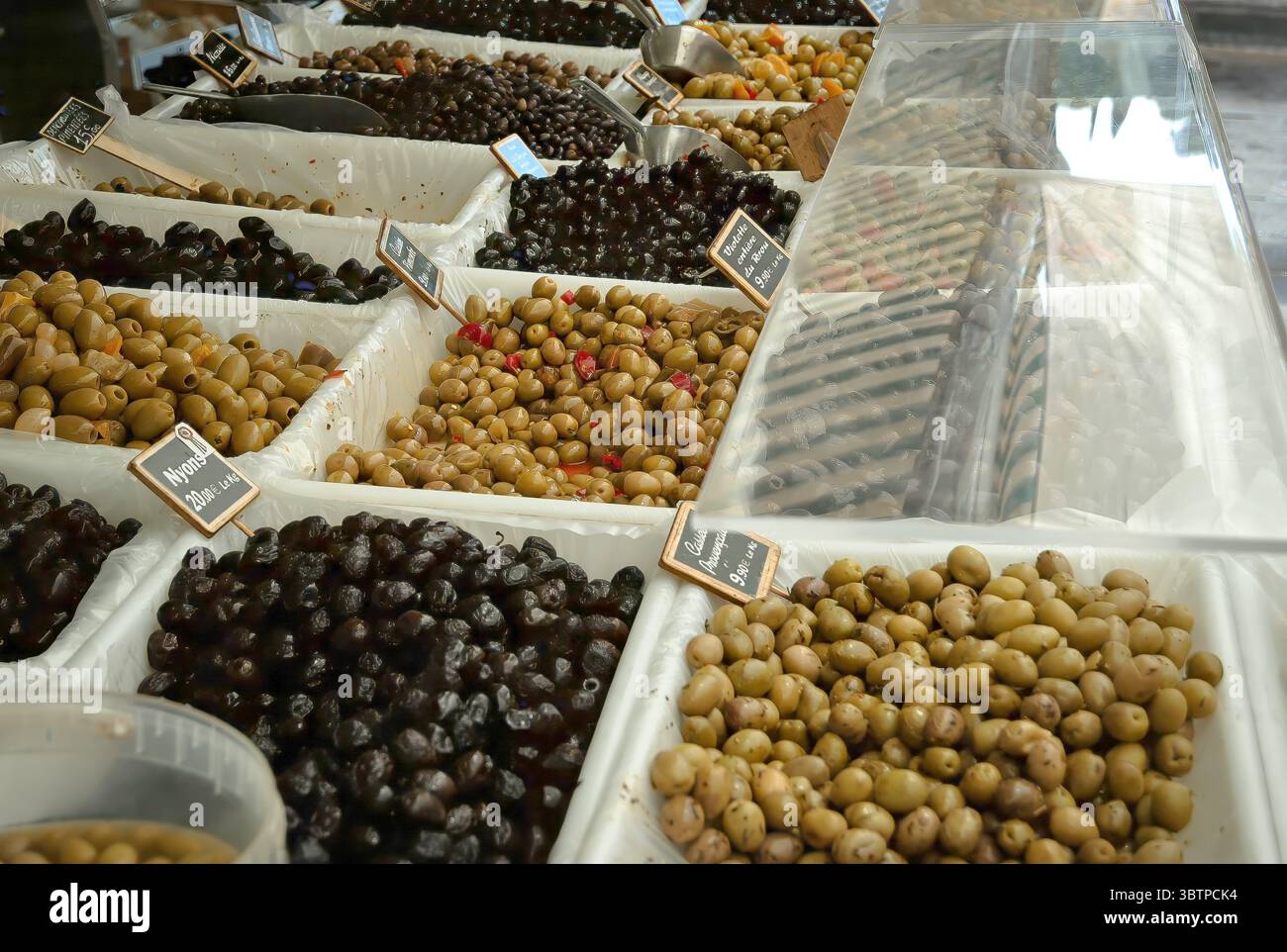 Various types of green and black olives displayed in open containers at ...