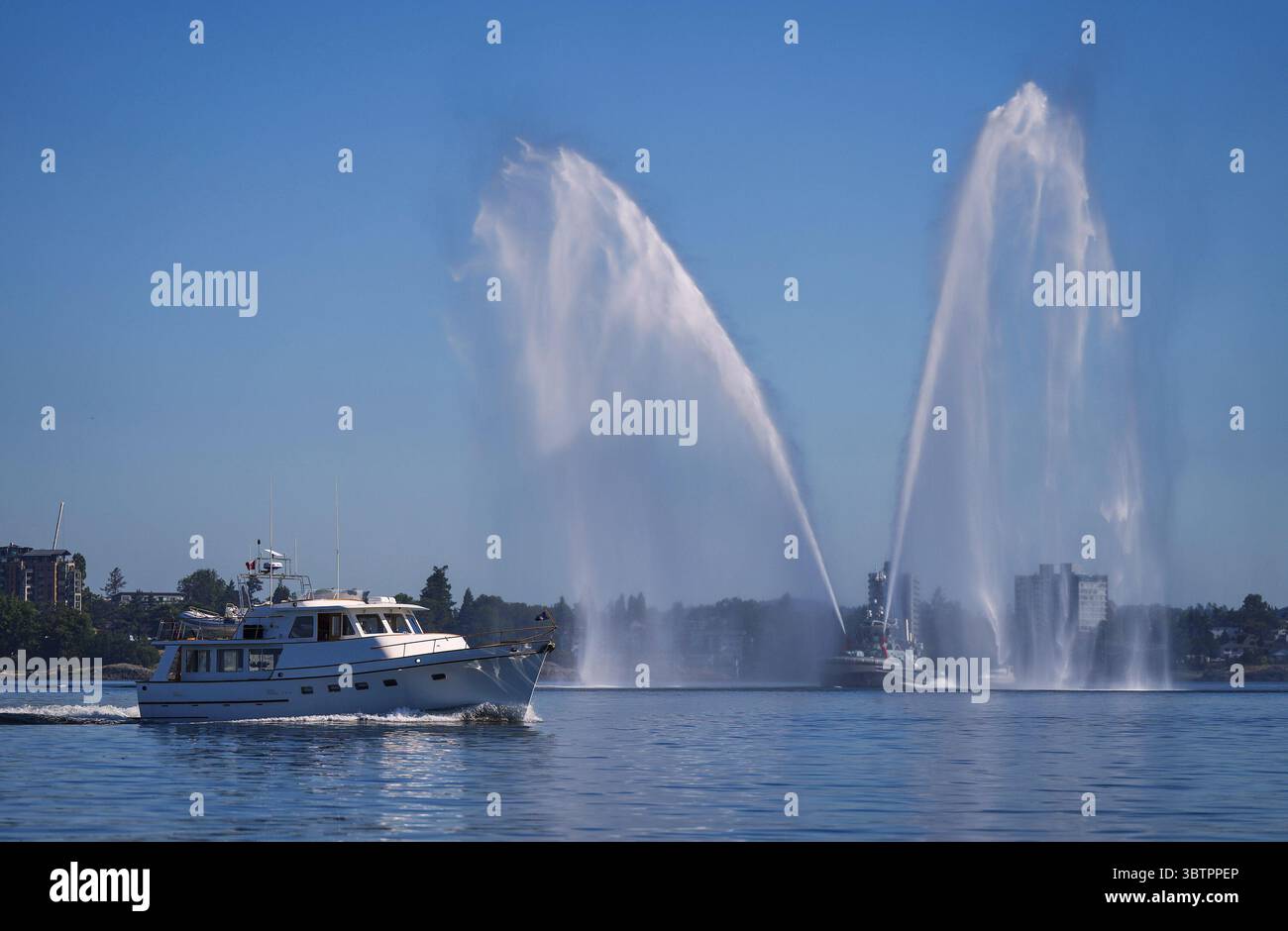 A pleasure craft boat passes by as a Royal Canadian Navy tug sprays ...