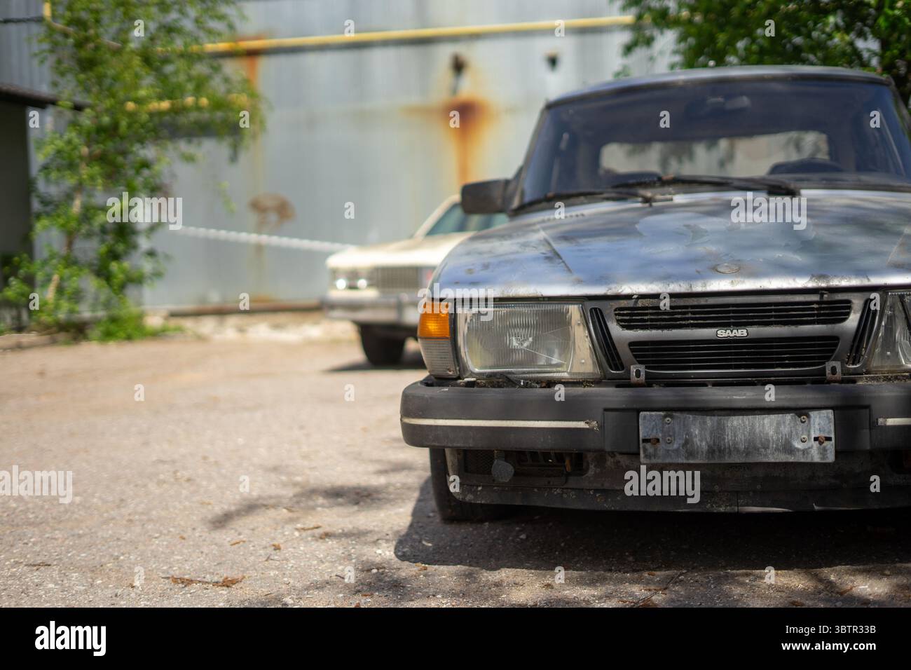 Vintage Saab car parked beside a rusted industrial wall, representing ...