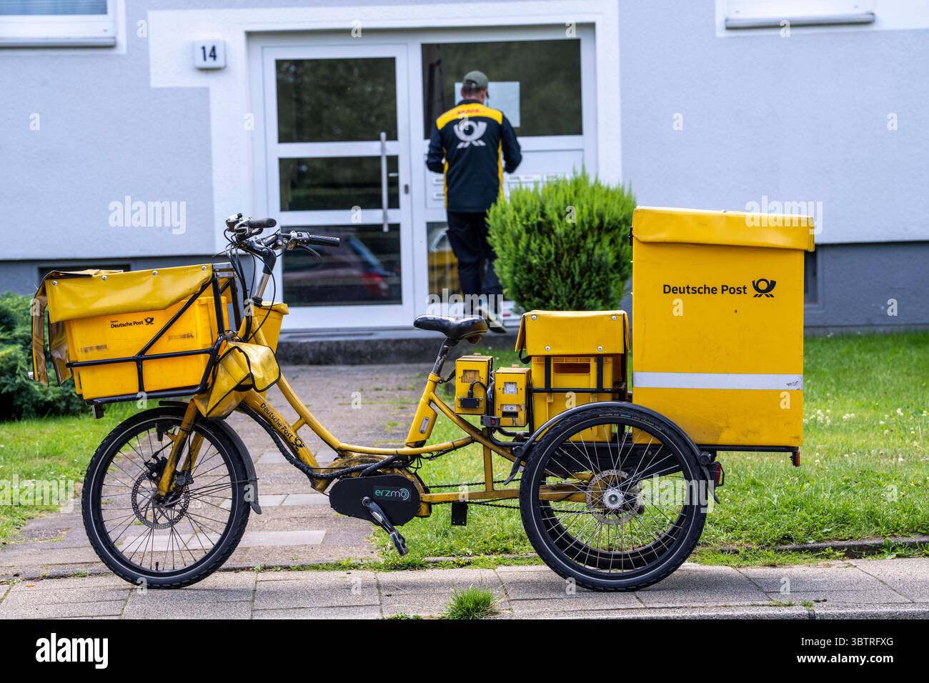 Postbote, Deutsche Post, verteilt die Post in einem Mehrfamilienhaus ...