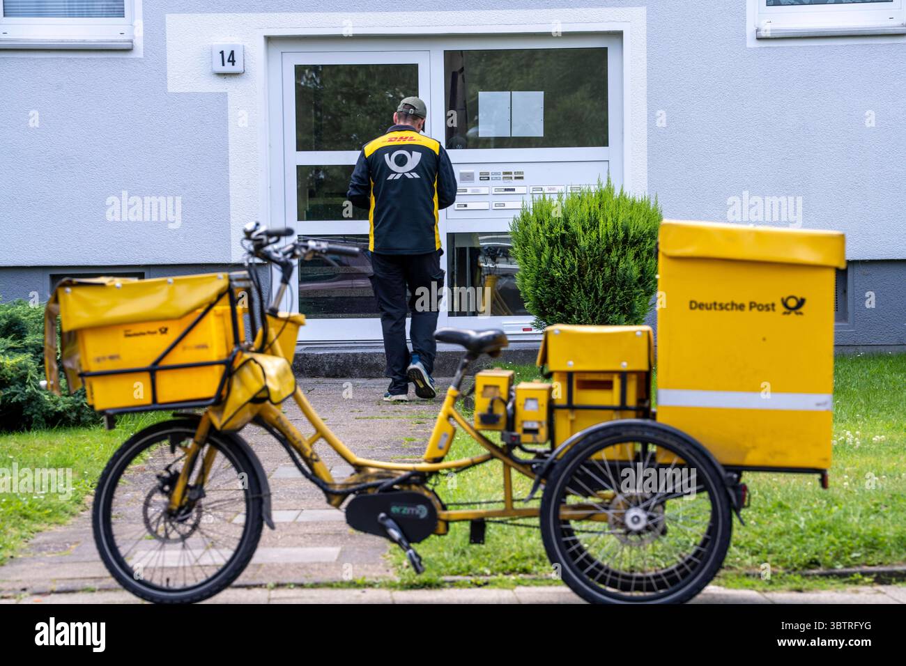 Postbote, Deutsche Post, verteilt die Post in einem Mehrfamilienhaus ...