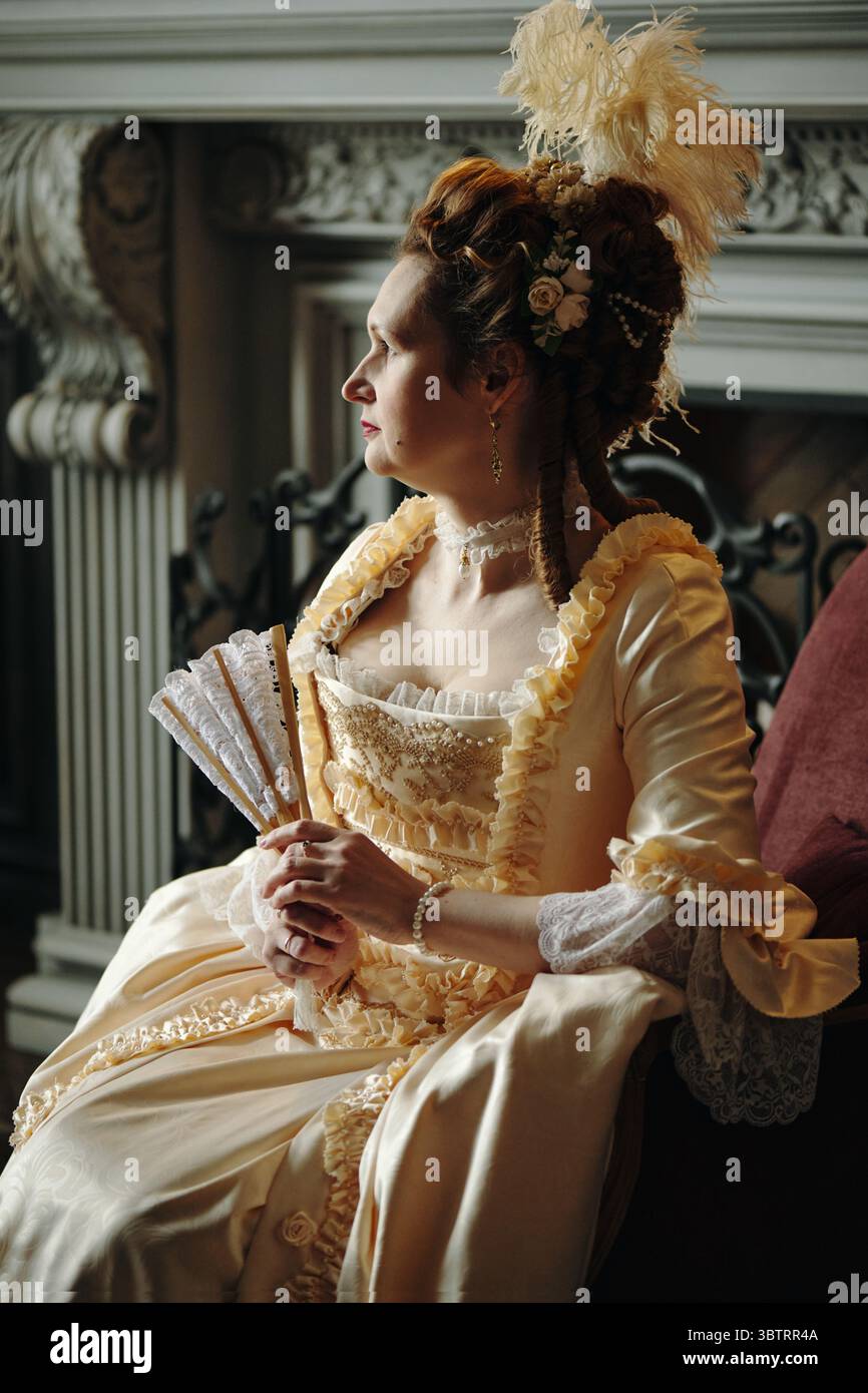 Caucasian middle aged woman sitting in profile holding folding fan ...