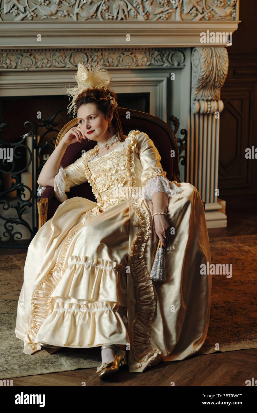 Caucasian young adult woman sitting in ornate chair wearing elaborate ...