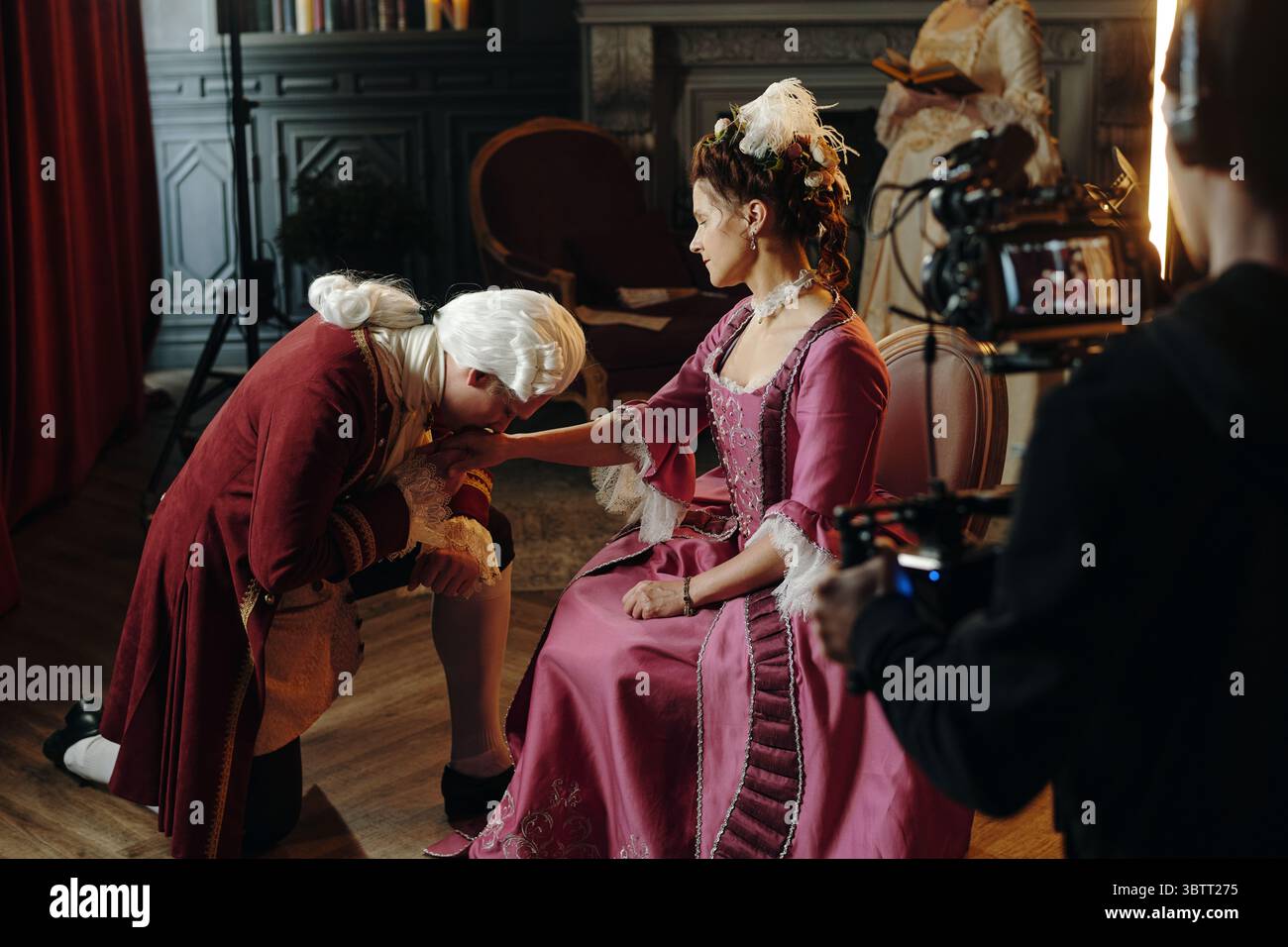Man in Baroque costume kneeling and kissing hand of seated Caucasian ...