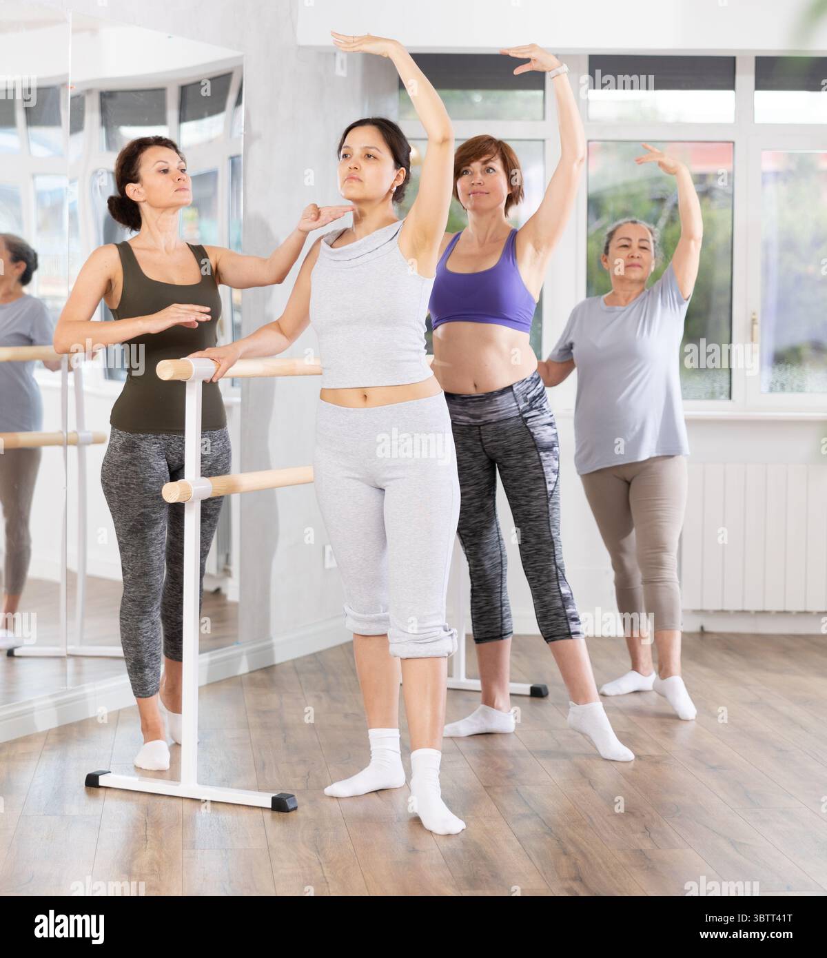 Group of women participating beginner ballet class with instructor ...