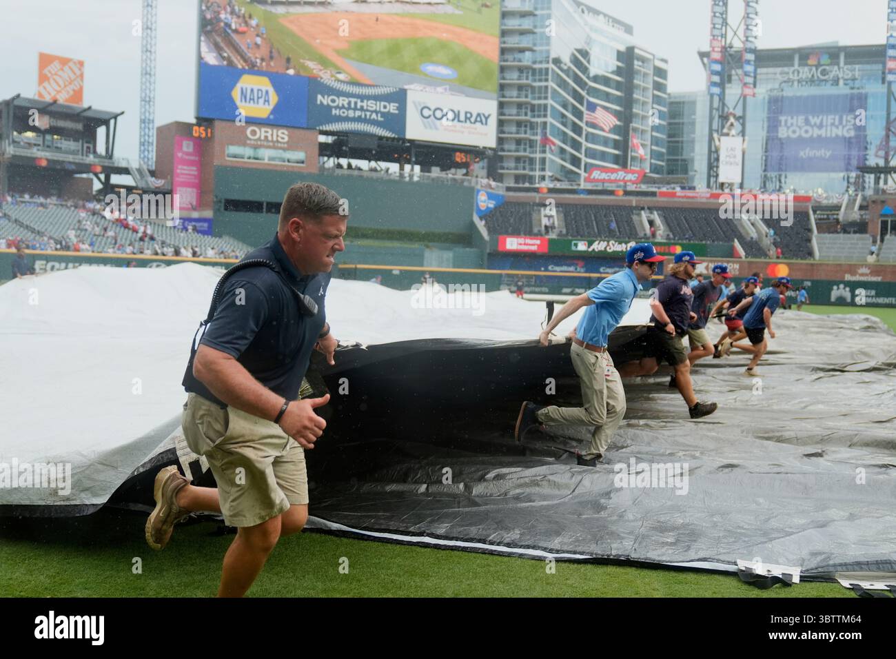 Ground crew members cover the field before the MLB baseball All-Star ...