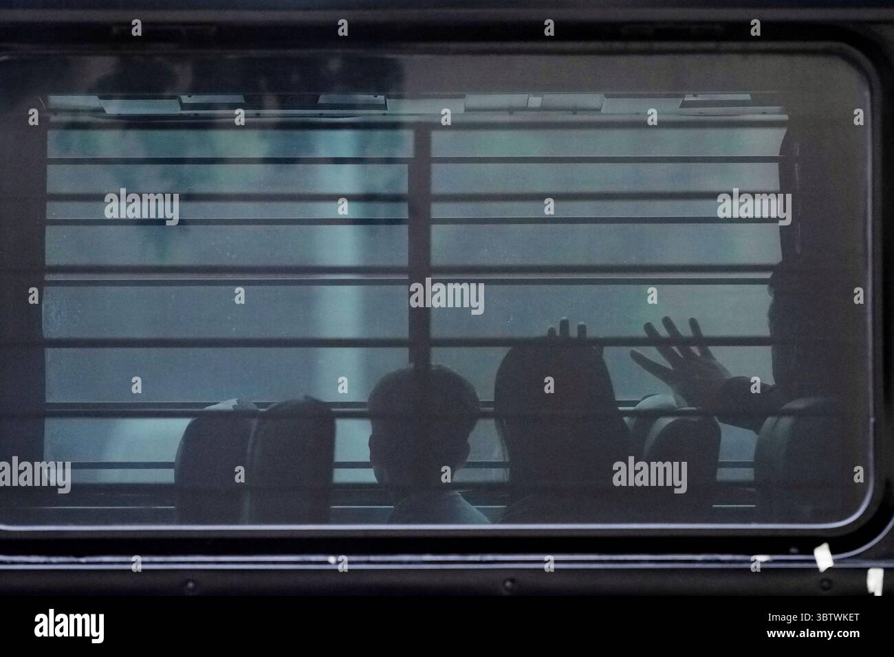 FILE - A family from Cuba is detained and loaded onto a bus with tinted windows and bars ...