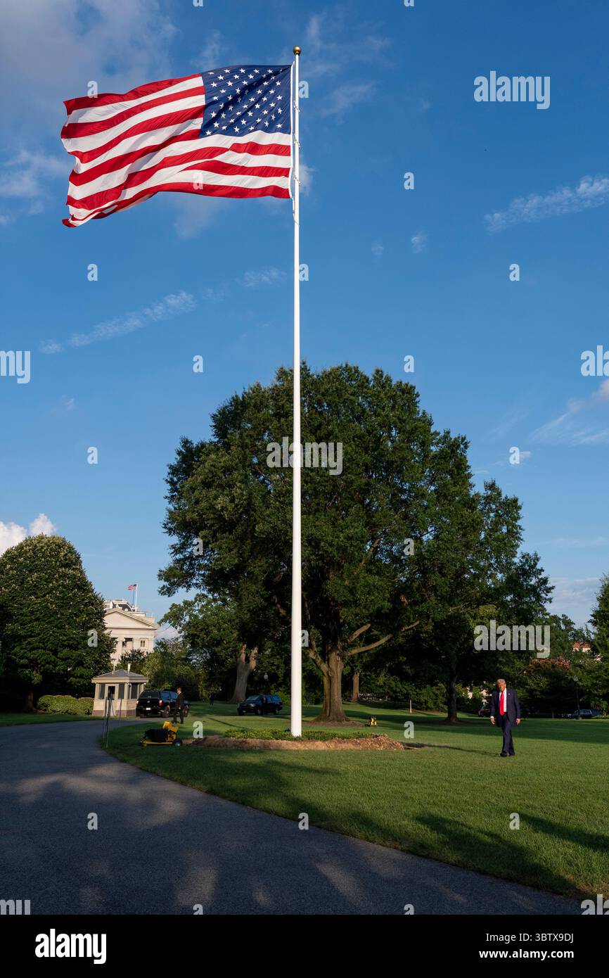 President Donald Trump looks at the work being done around the new flag ...