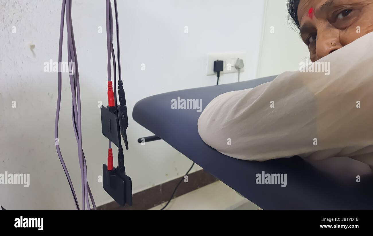 patient lying at plinth for physiotherapy session with electrode at ...