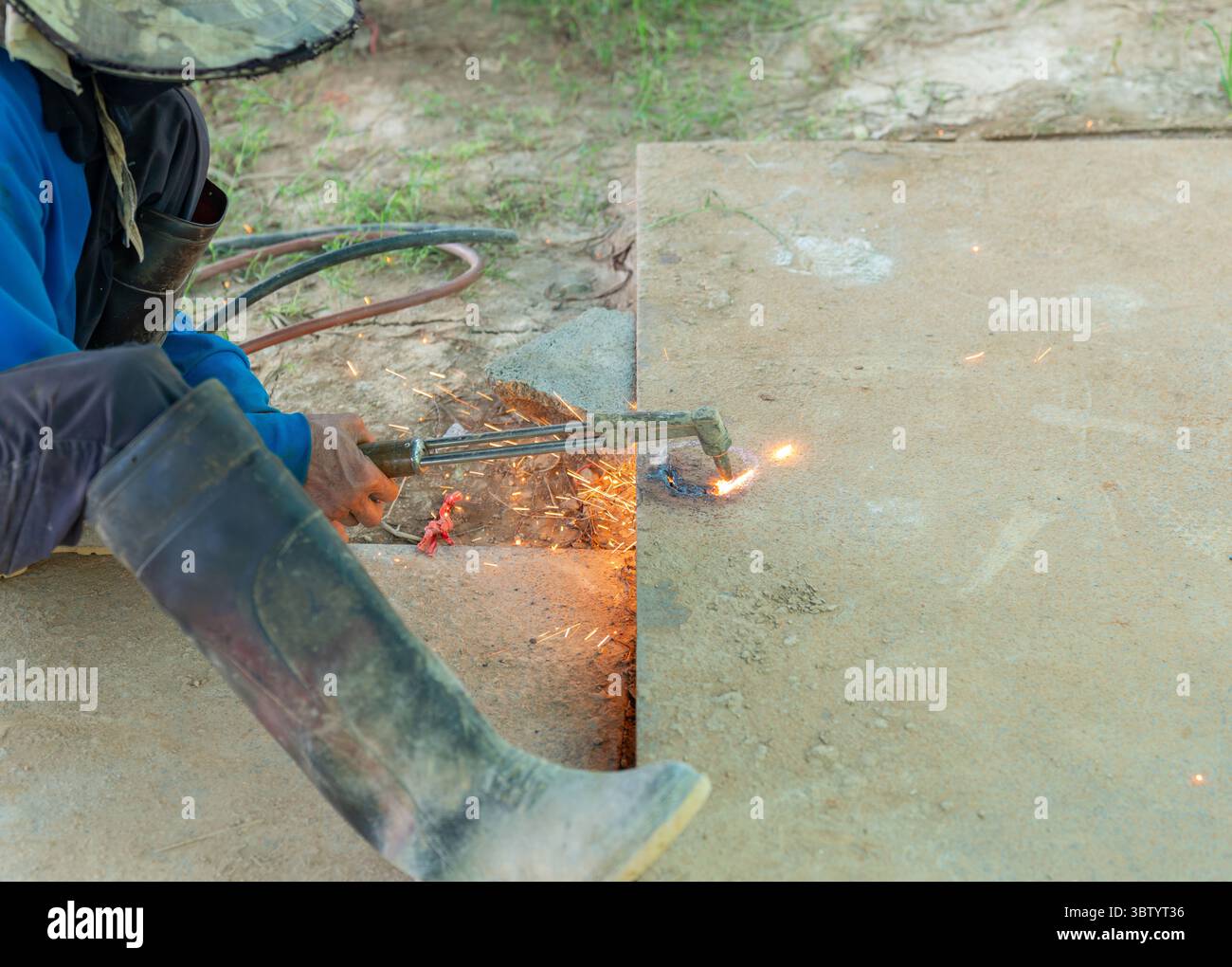 The worker is performing gas cutting on a steel sheet at construction ...