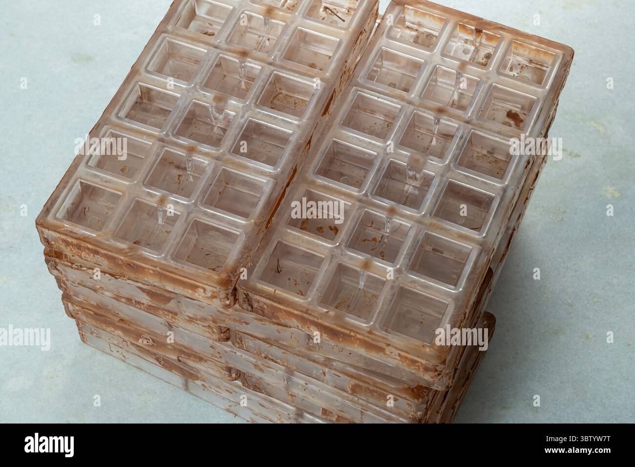 Dirty plastic molds for making chocolate squares Stock Photo - Alamy