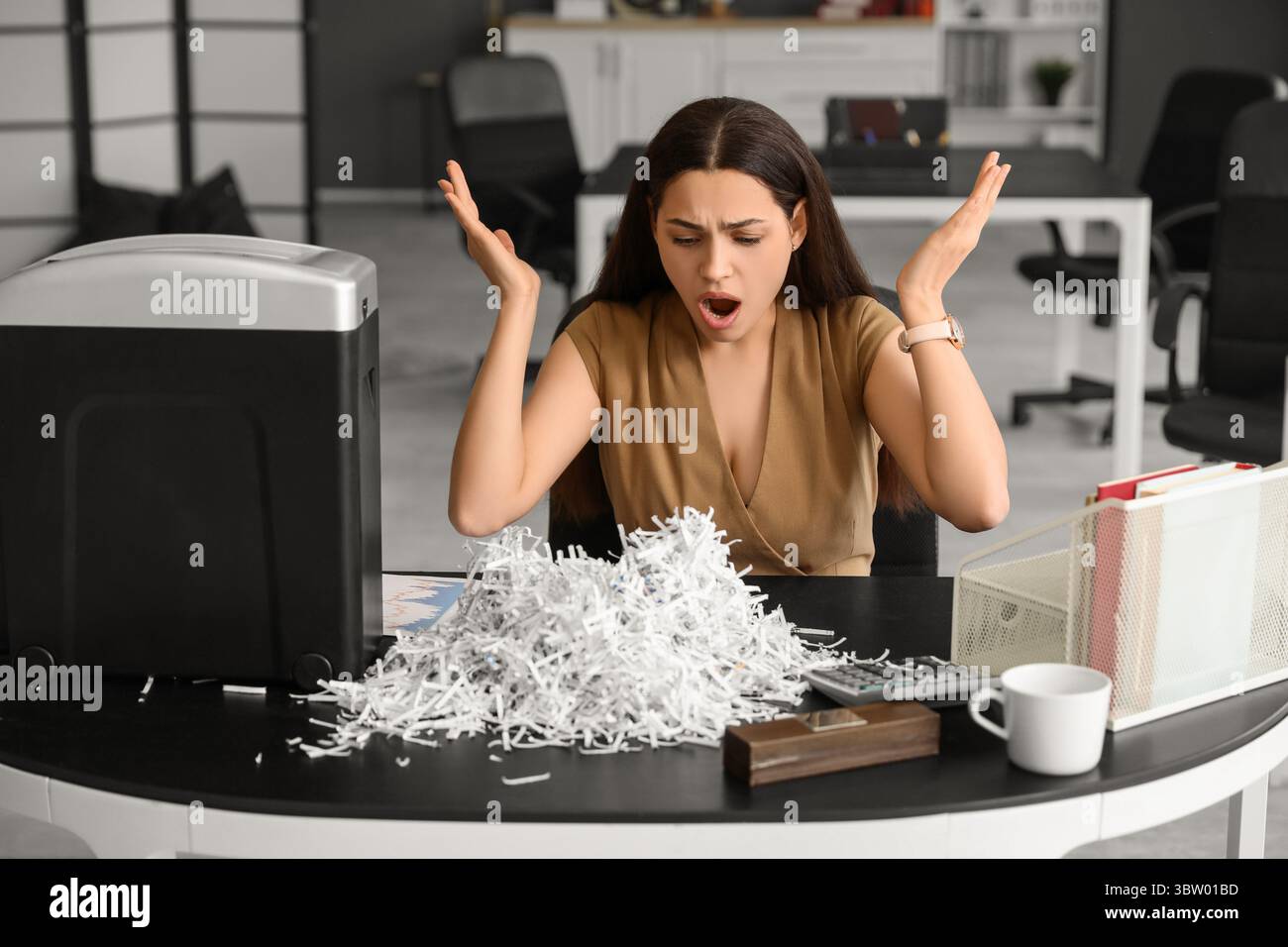 Shocked young secretary with shredded paper and shredder in office ...