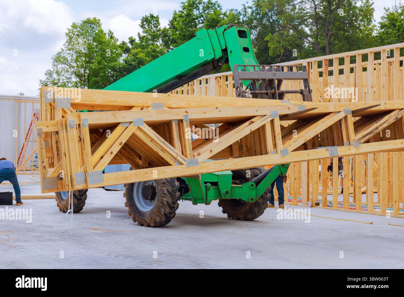 Workers use telehandler to lift wooden frames at construction site ...