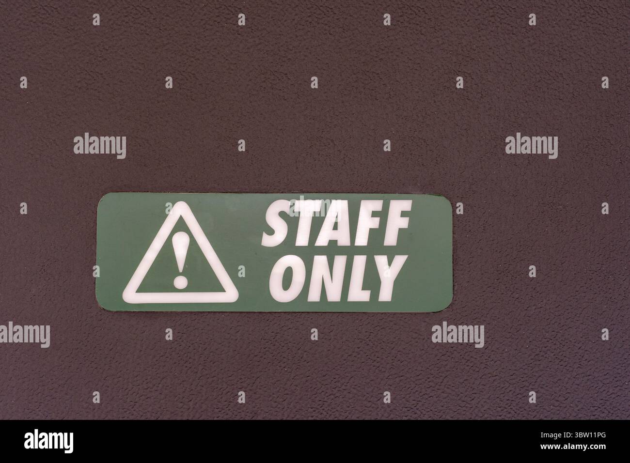 Close-up of a "STAFF ONLY" sign with a warning symbol on a dark ...