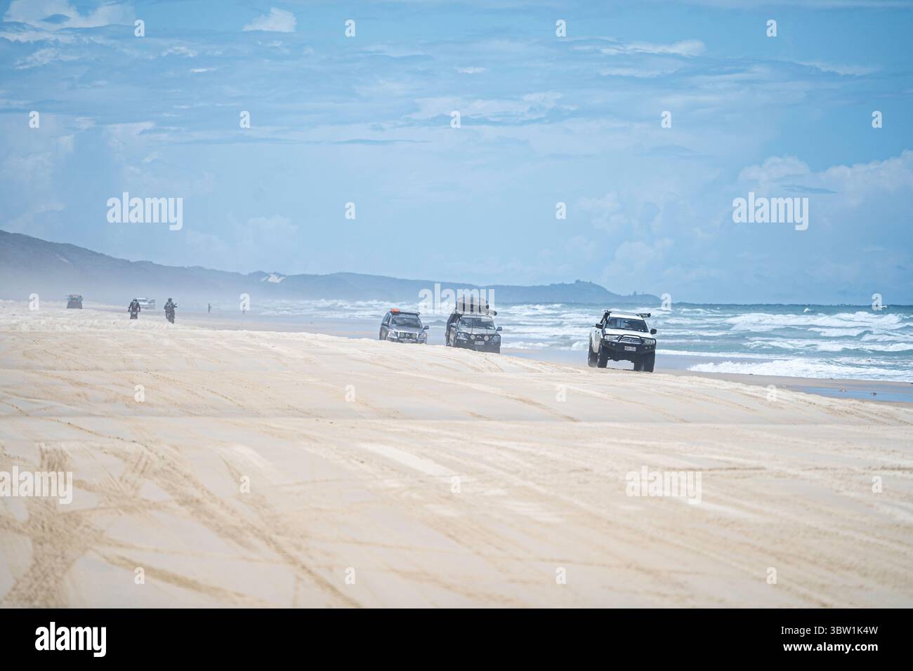 Multiple 4WD vehicles driving on wide sandy beach, Teewah Beach, Great ...