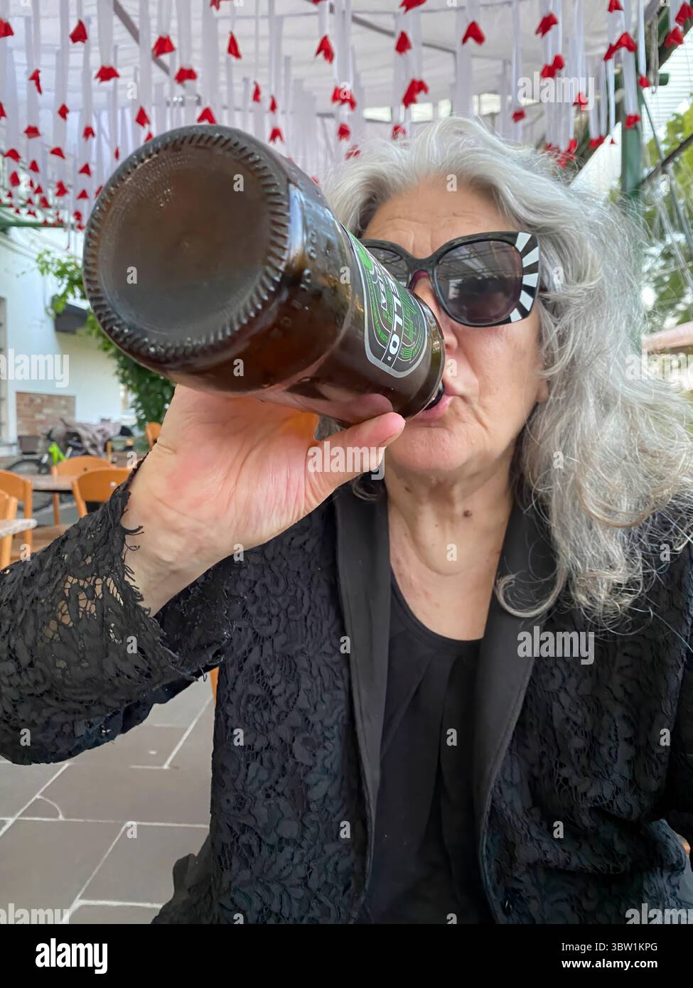 A Stylish Older Woman with Gray Hair and Sunglasses Enjoys a Refreshing ...