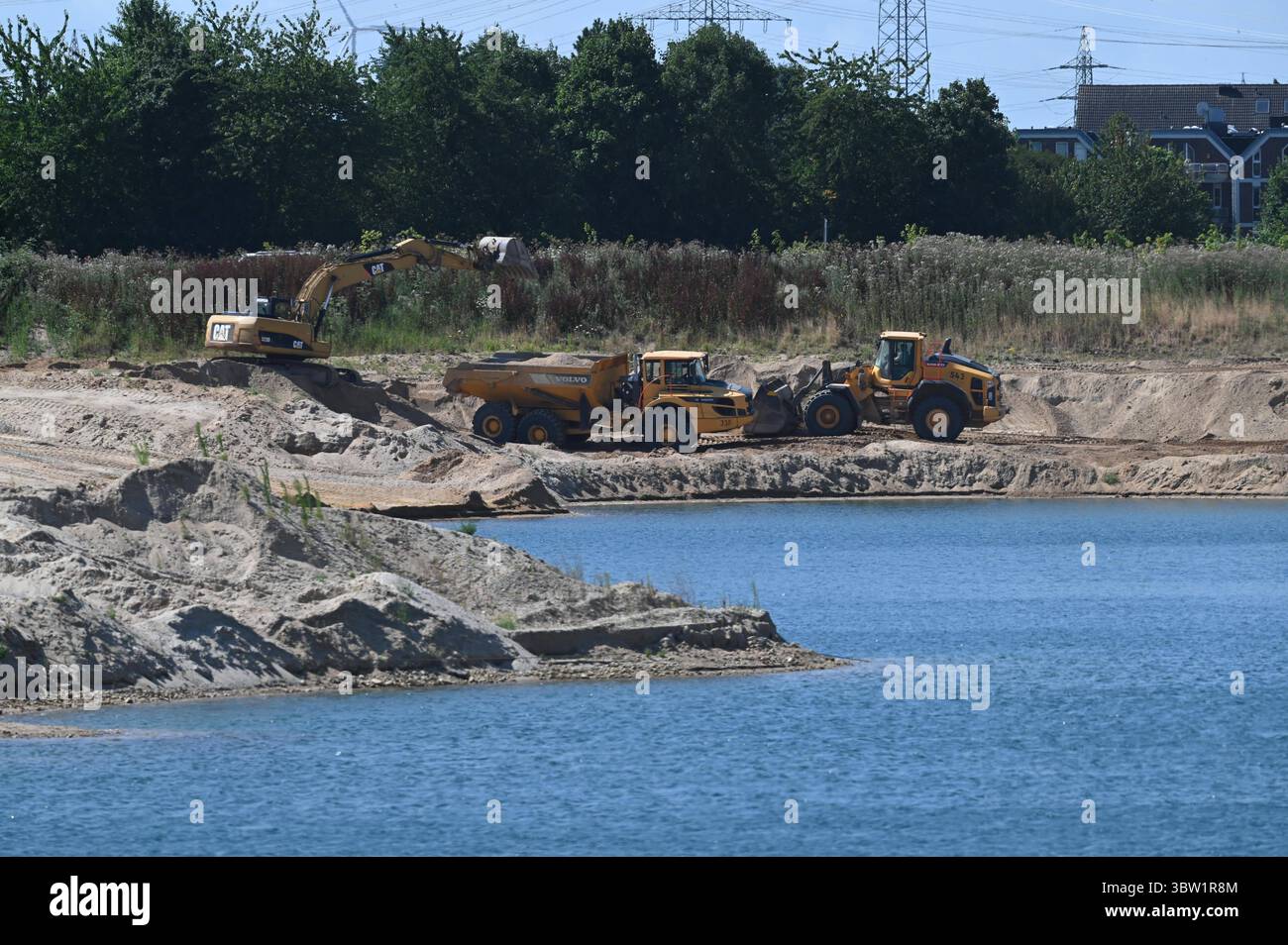 Ein Bagger laedt Sand auf einen Kipplaster, an einem Baggersee, am 15. ...