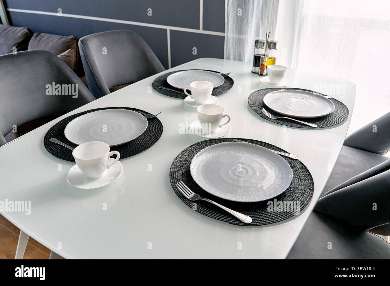 A sophisticated dining room features a glass table set with white ...