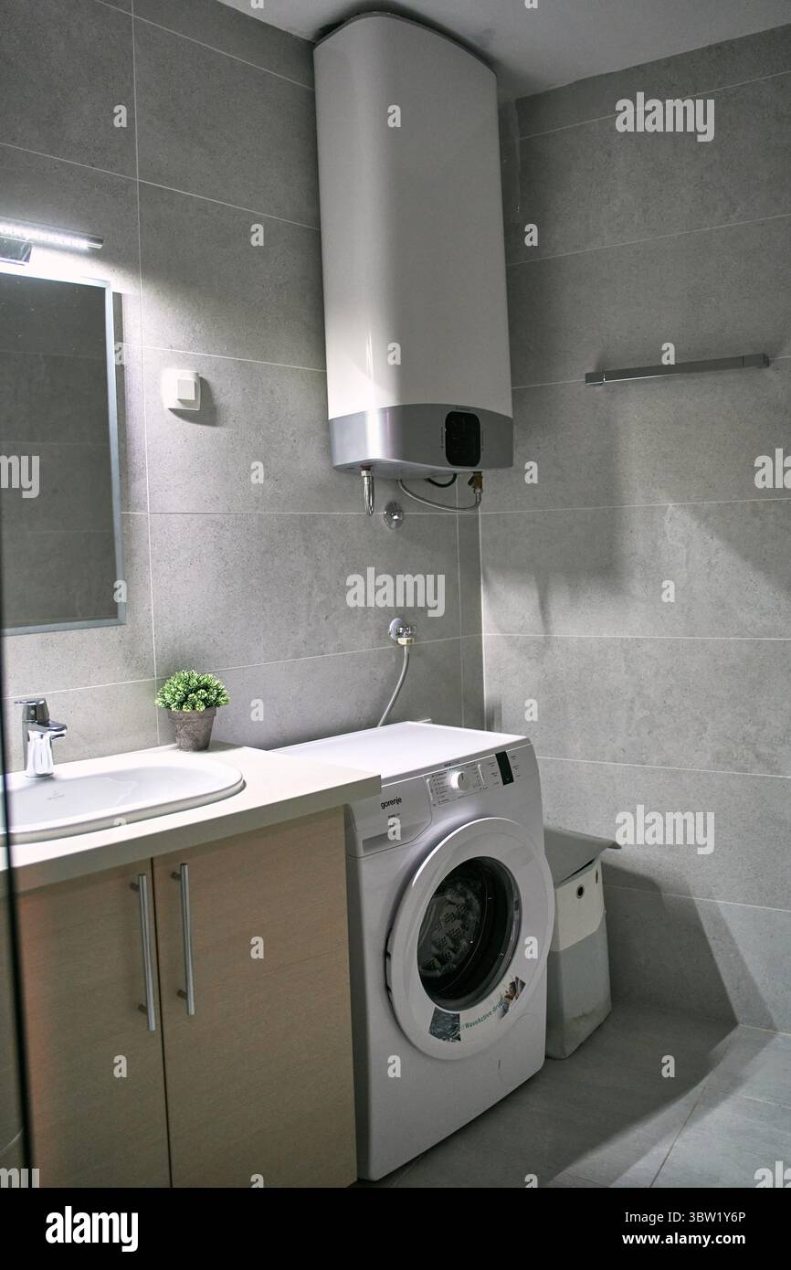 A modern bathroom features a front-loading washing machine and a wall ...